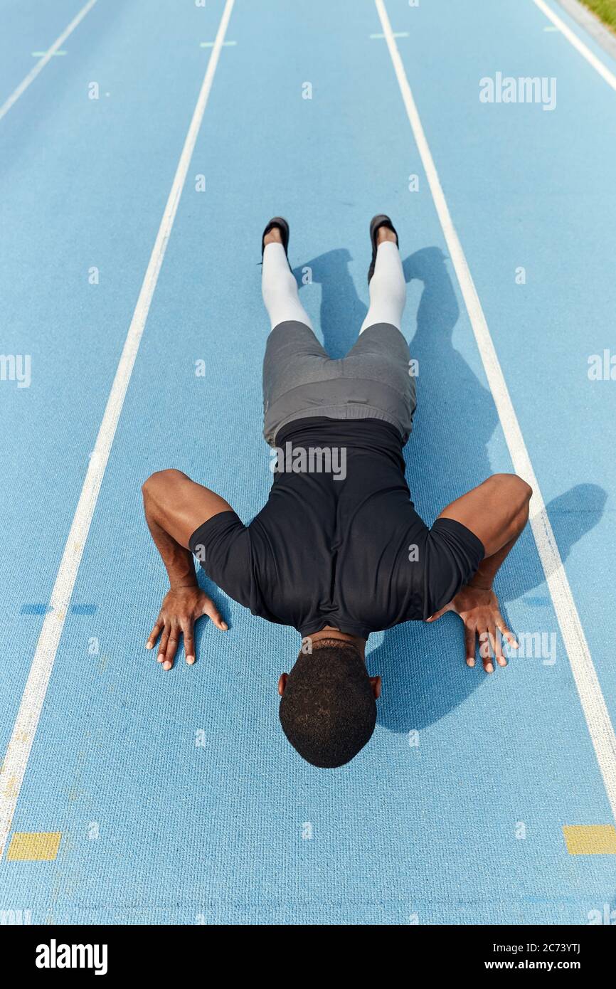 motivated african athletic young man doing push-ups at the stadium ...