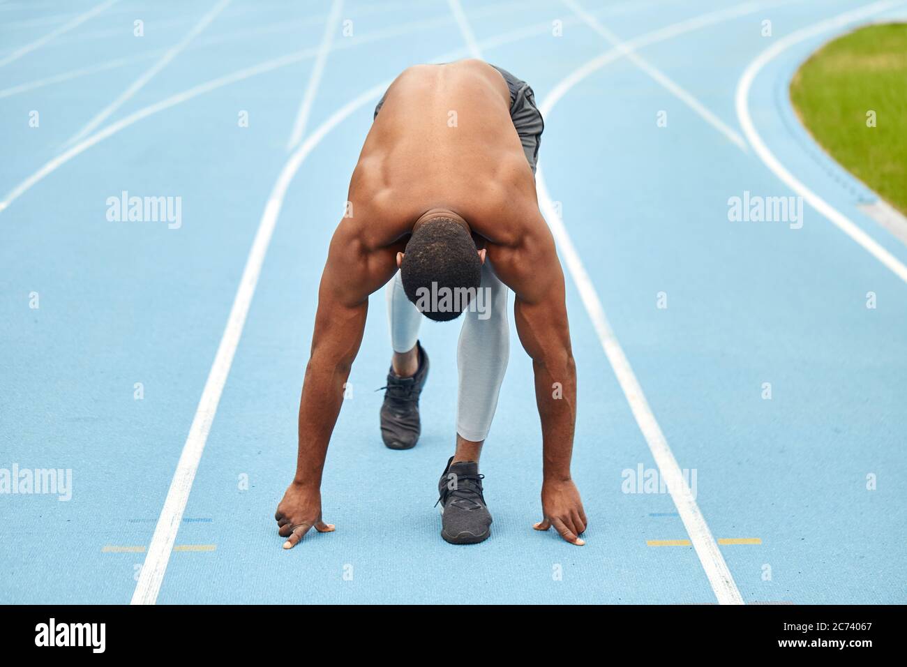 runner with strong muscular body training at the stadium, full length ...