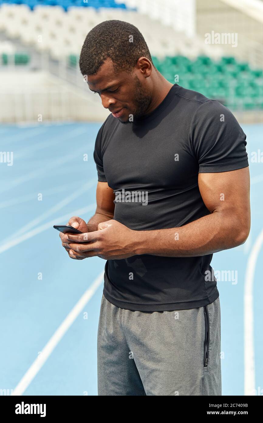 brutal strong muscular african guy typing something on his mobile smart ...