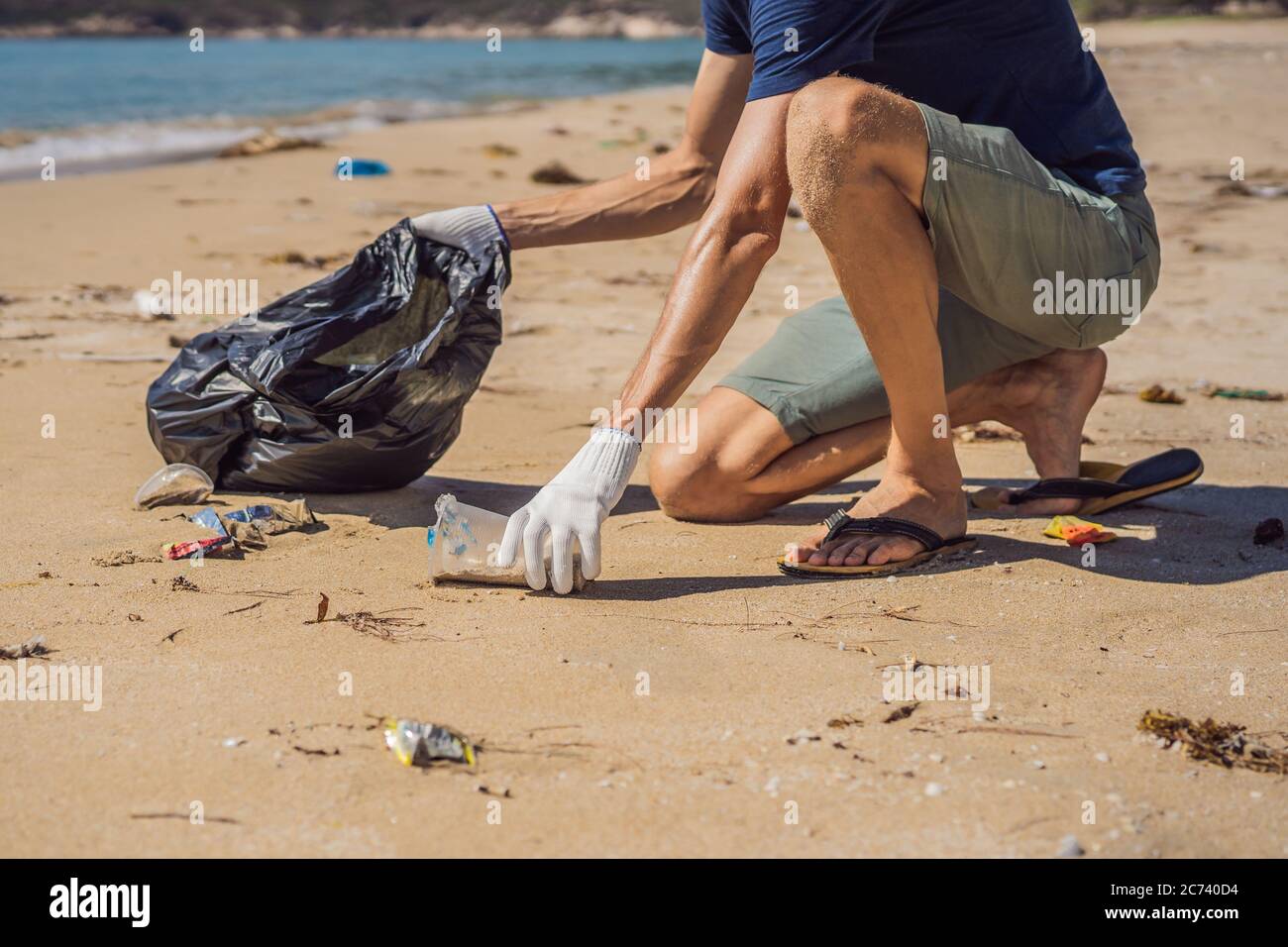 Man in gloves pick up plastic bags that pollute sea. Problem of spilled ...