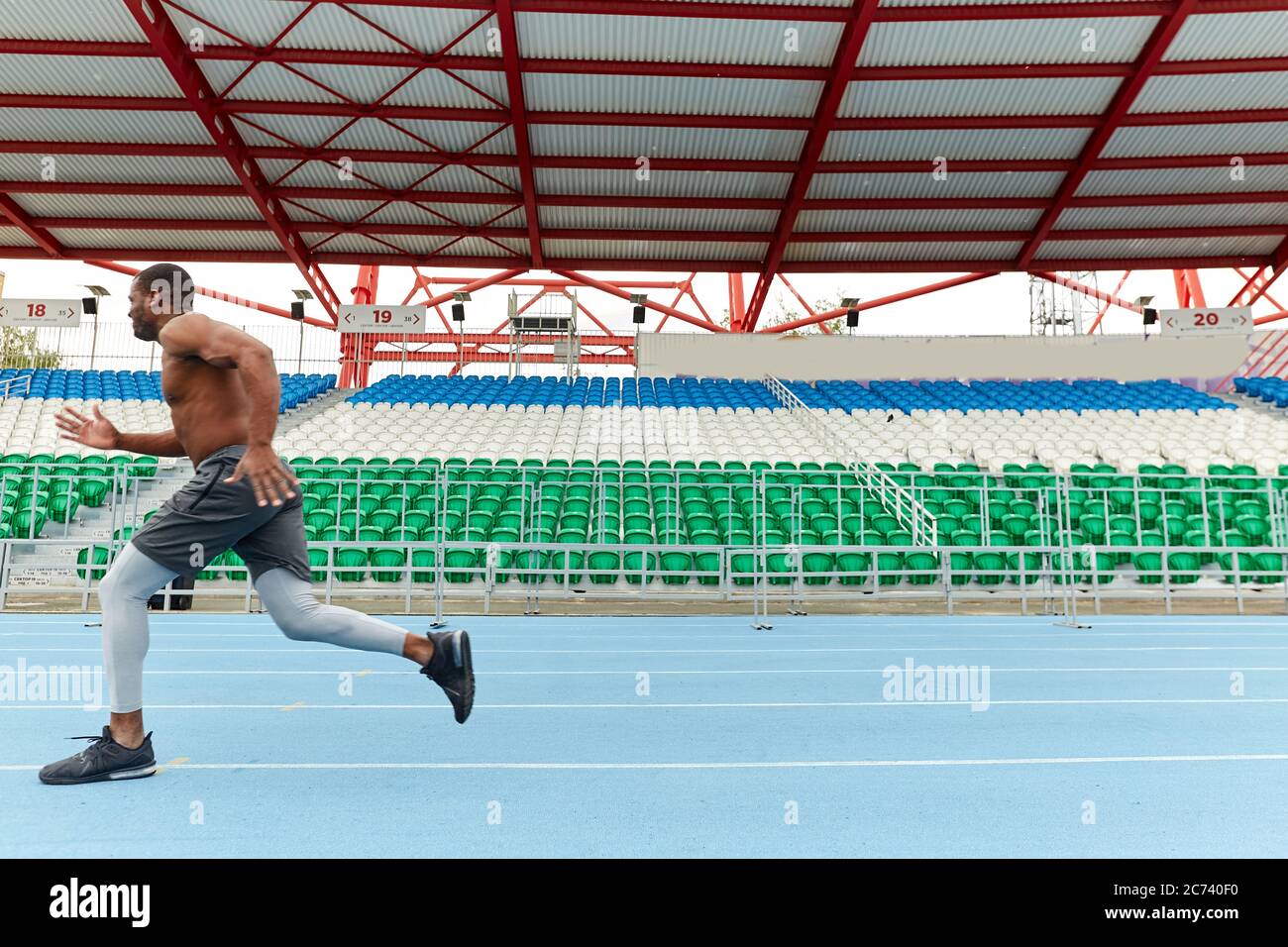 fast motivated athllete sprinting on running track, full length side ...