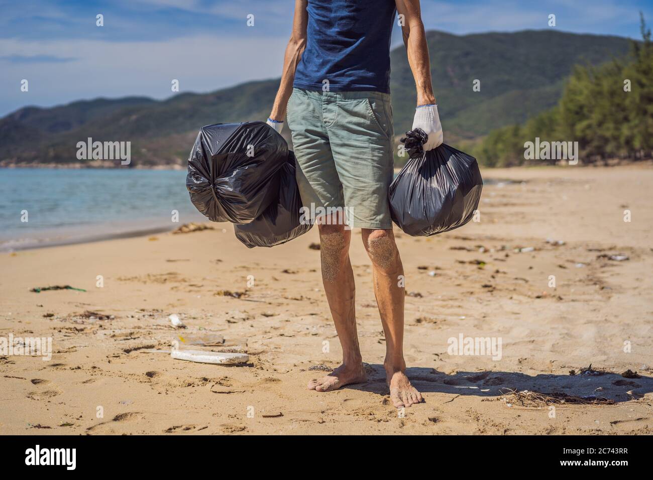 Man in gloves pick up plastic bags that pollute sea. Problem of spilled ...