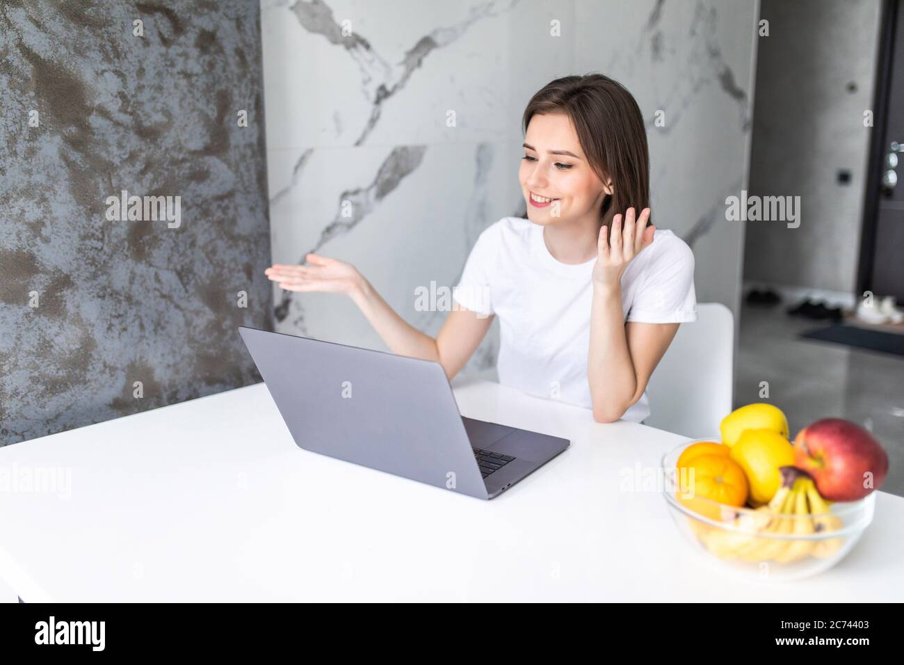 Young woman sit at desk in kitchen have video call on modern computer ...