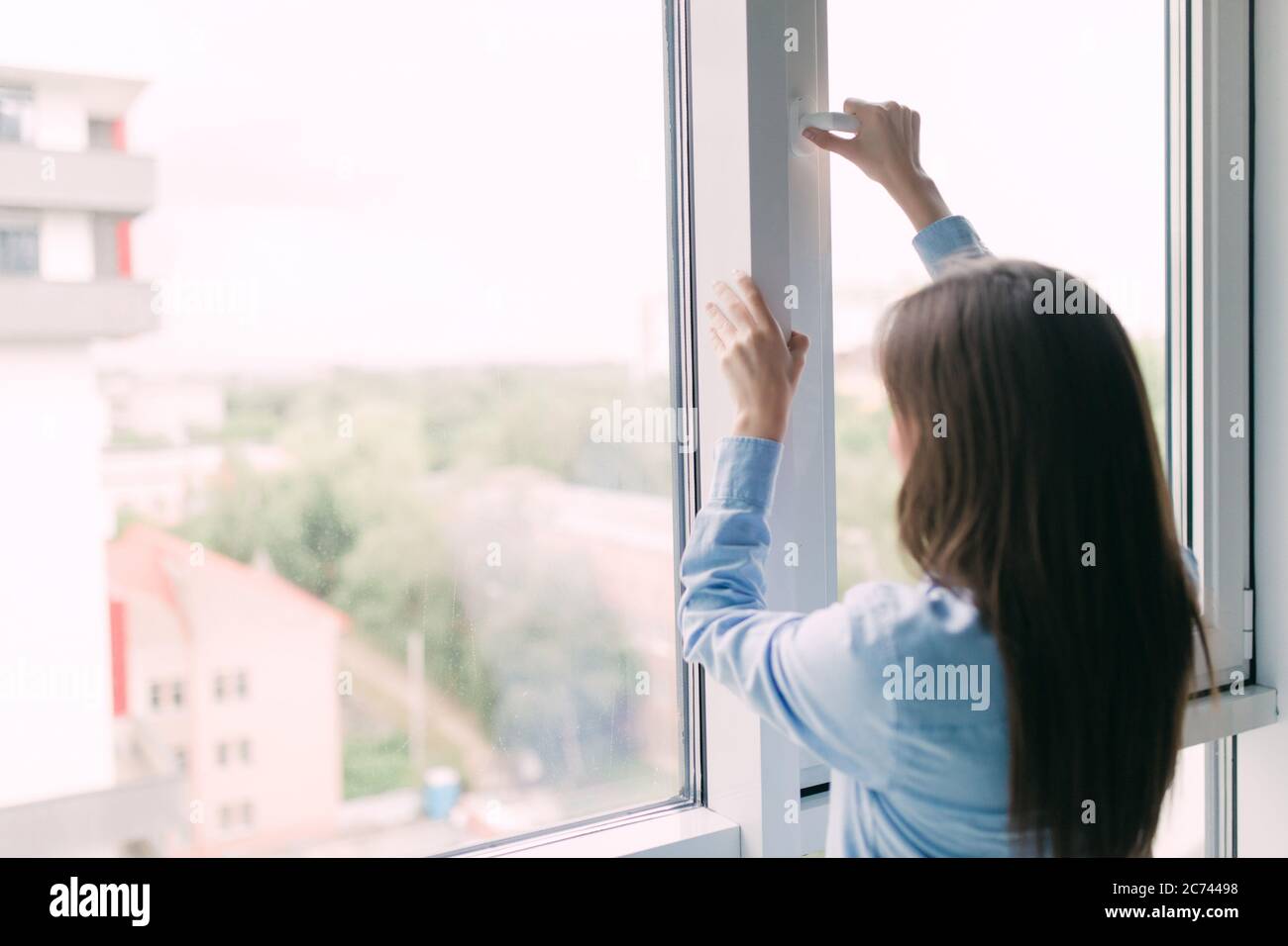 Young woman opening window in living room Stock Photo - Alamy