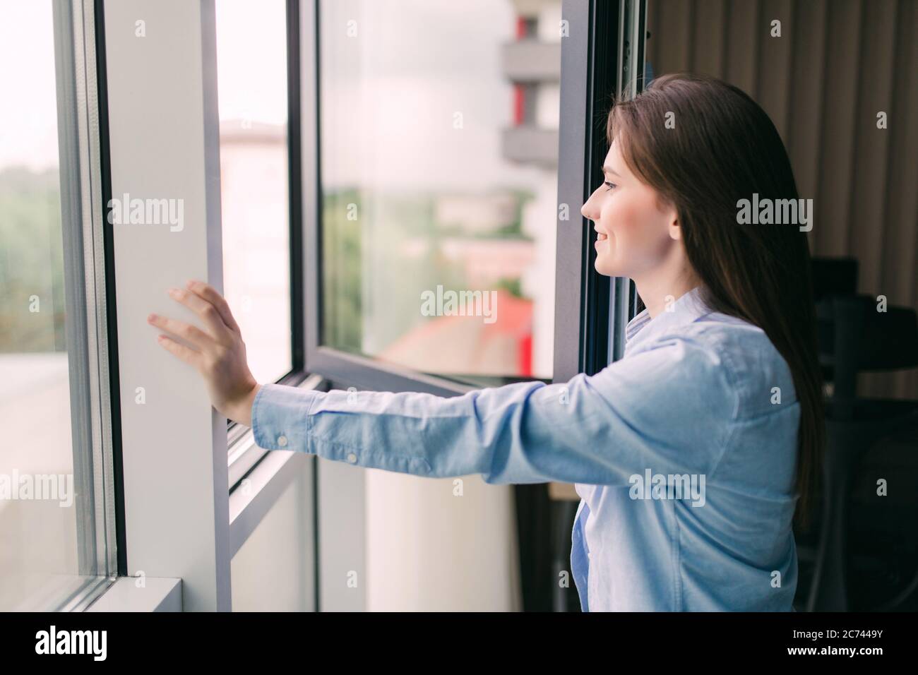 Young woman opening window in living room Stock Photo - Alamy