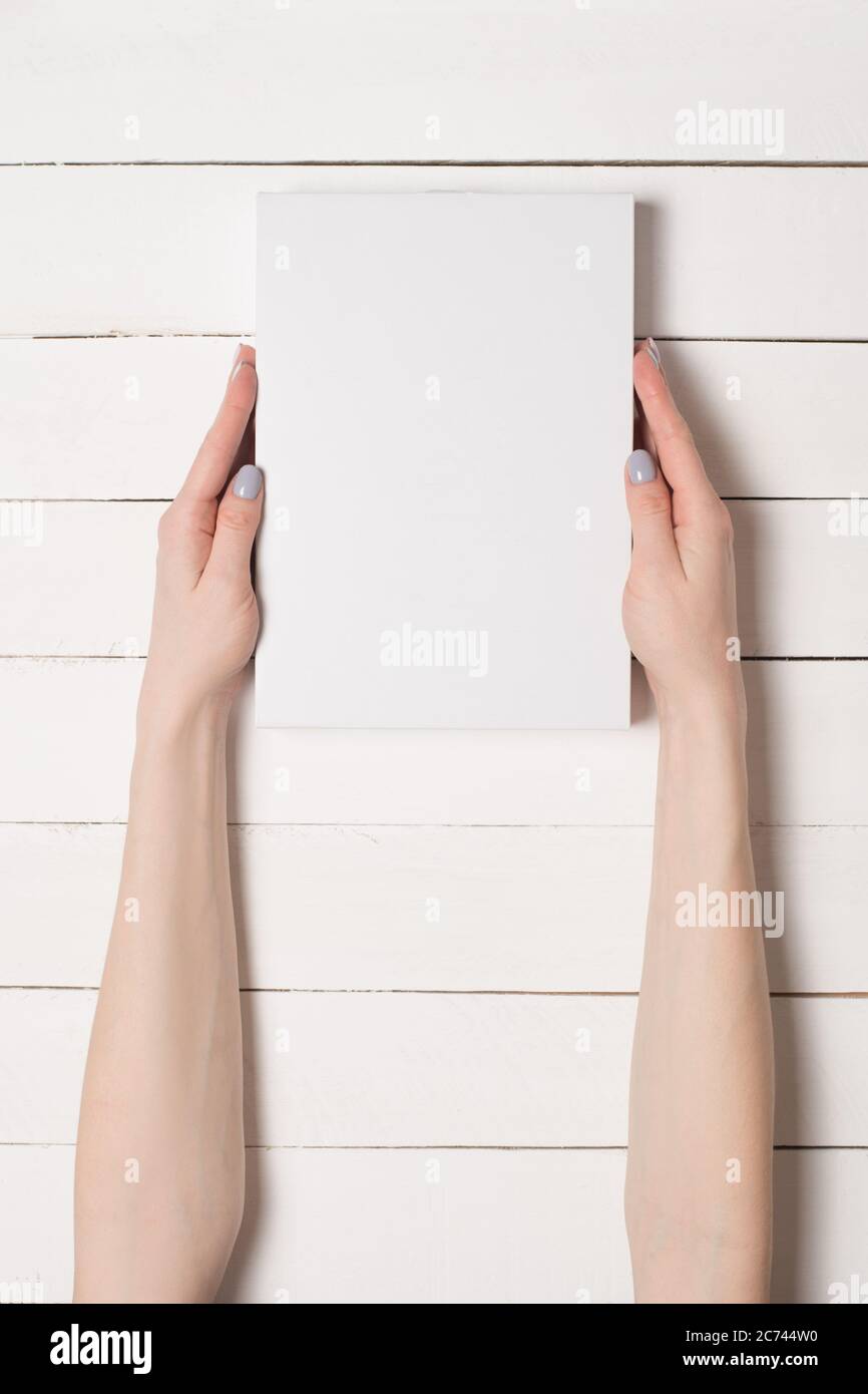 White rectangular box in female hands. Top view. White table on the ...