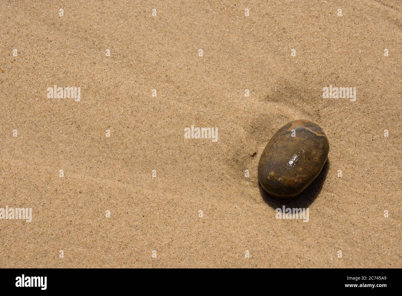 A single smooth beach pebbles against a background of smooth water ...