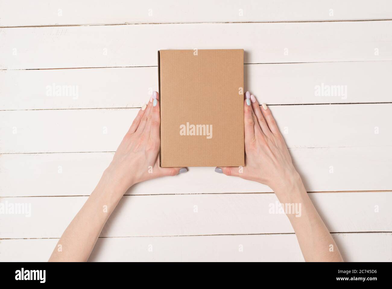 Rectangular box in female hands. Top view. White table on the ...