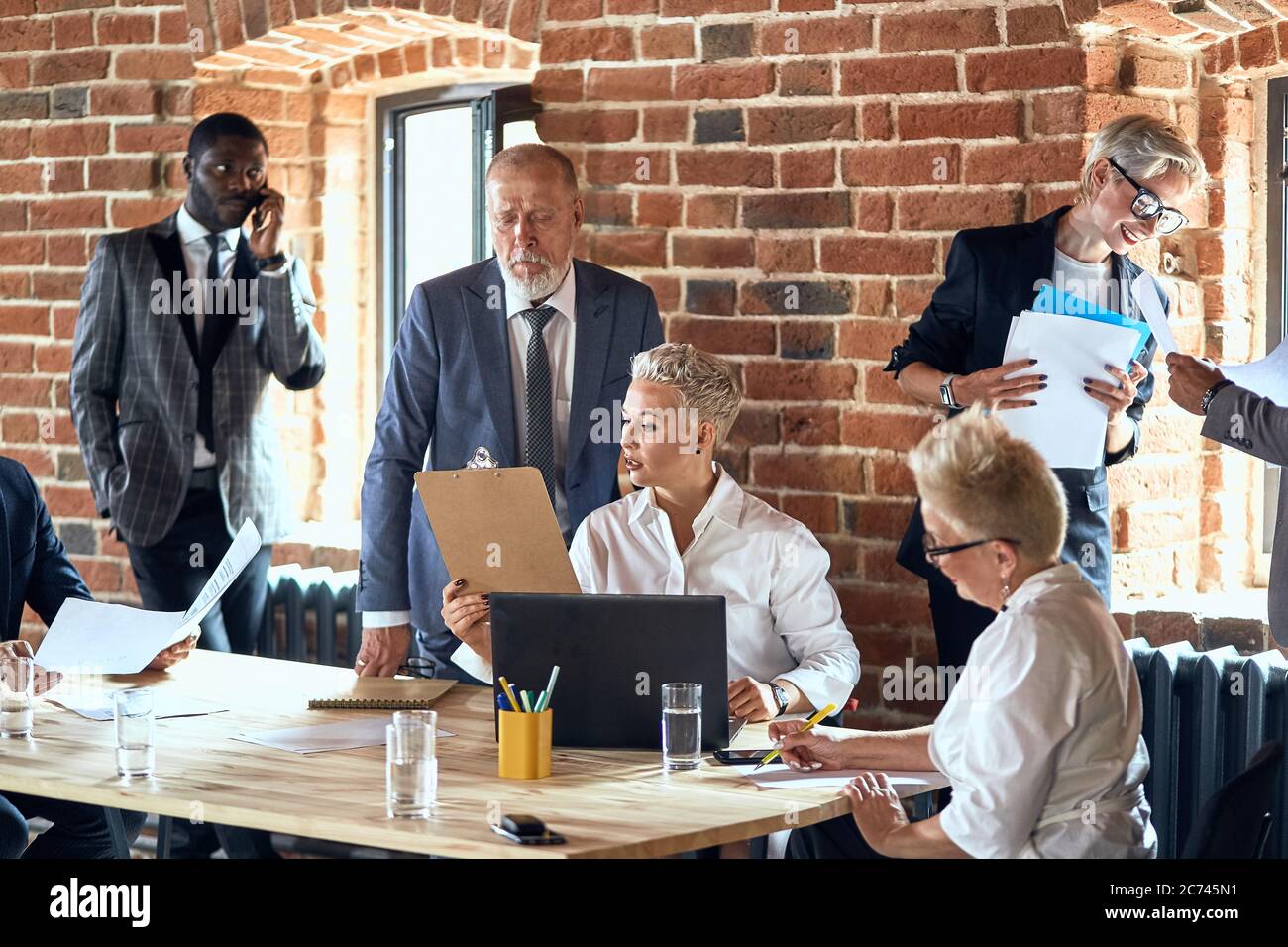 Group of people wear stylish suits work in office at table, ohter near ...