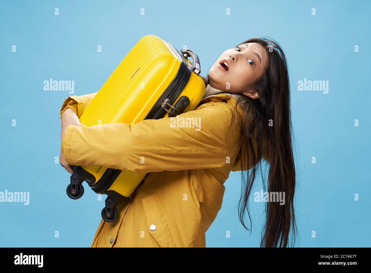 Woman with a heavy suitcase go on a trip on a blue background model ...