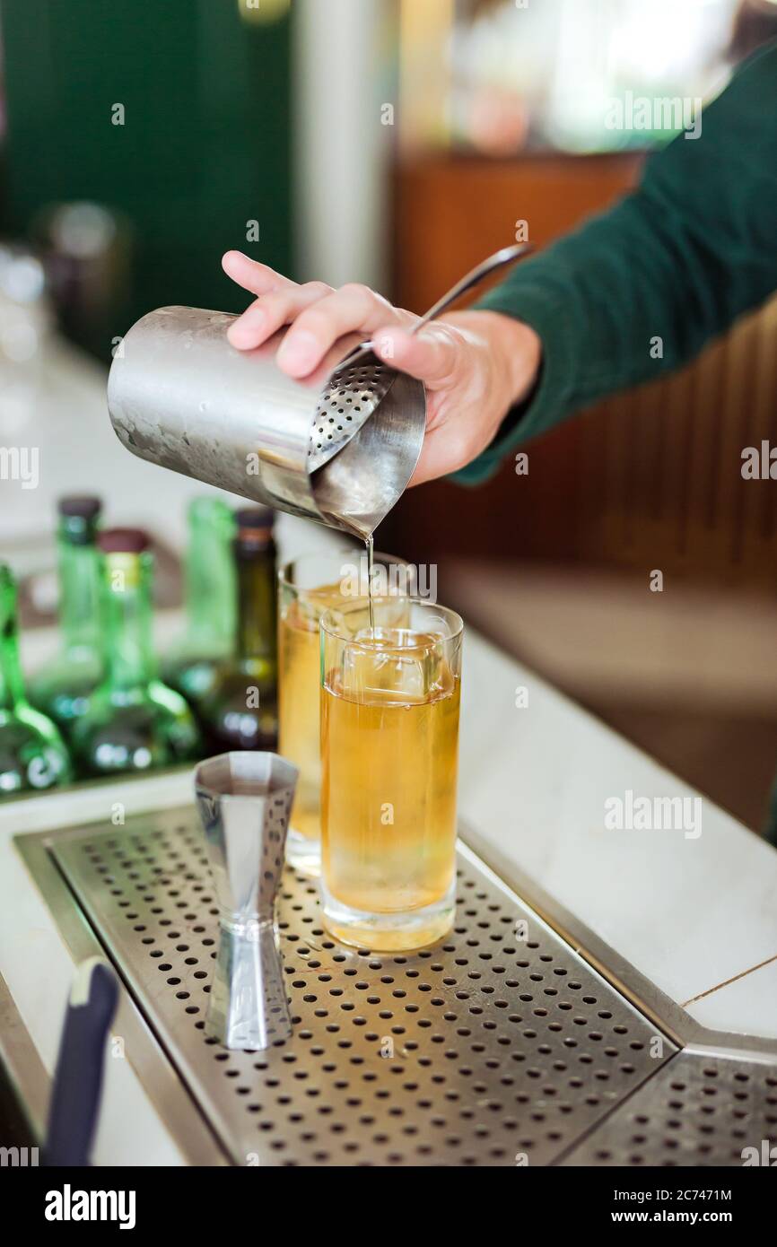 Bartender making a cocktail at the bar: pouring a drink from a shaker ...