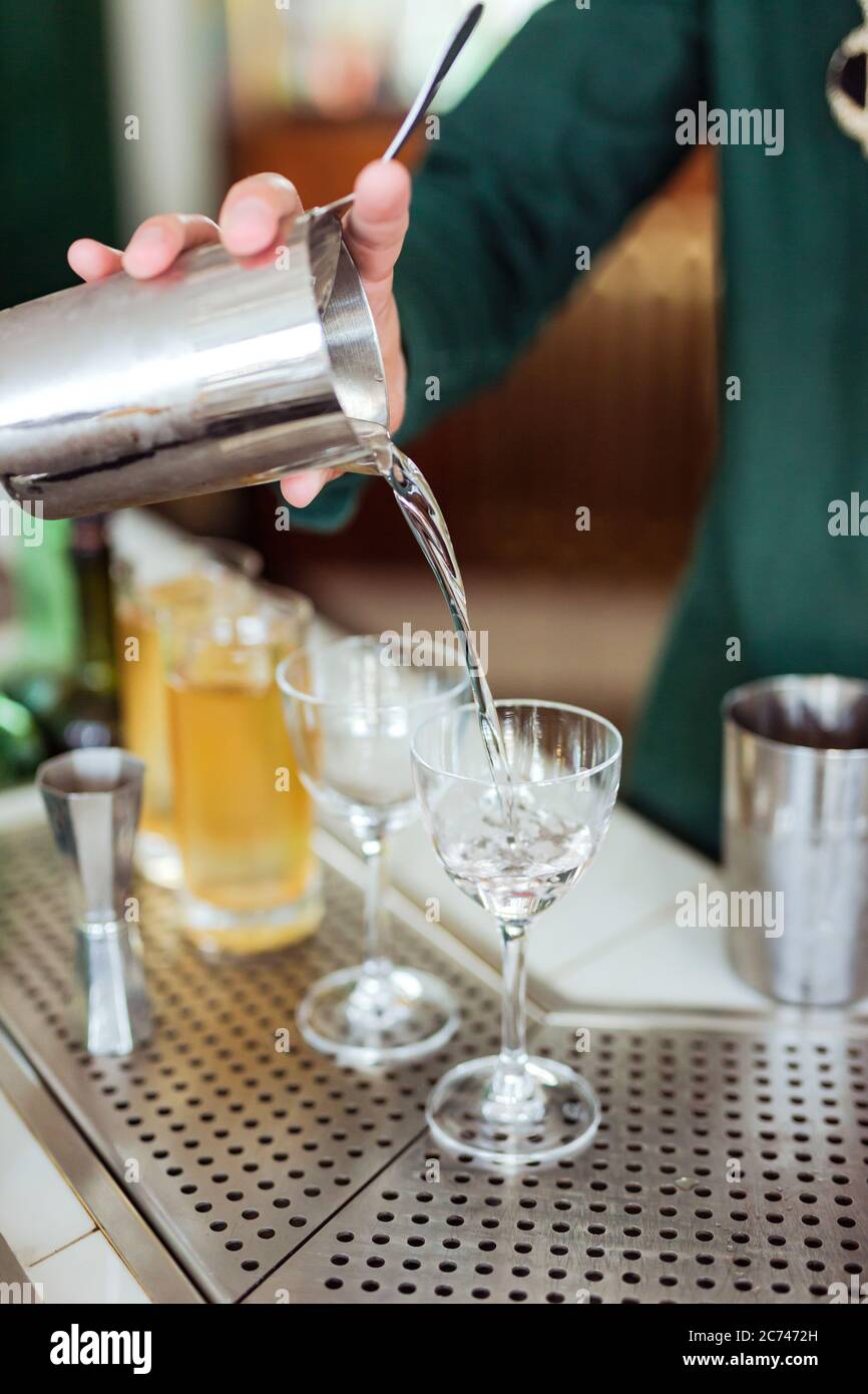 Bartender making a cocktail at the bar: pouring a drink from a shaker into a glass Stock Photo ...