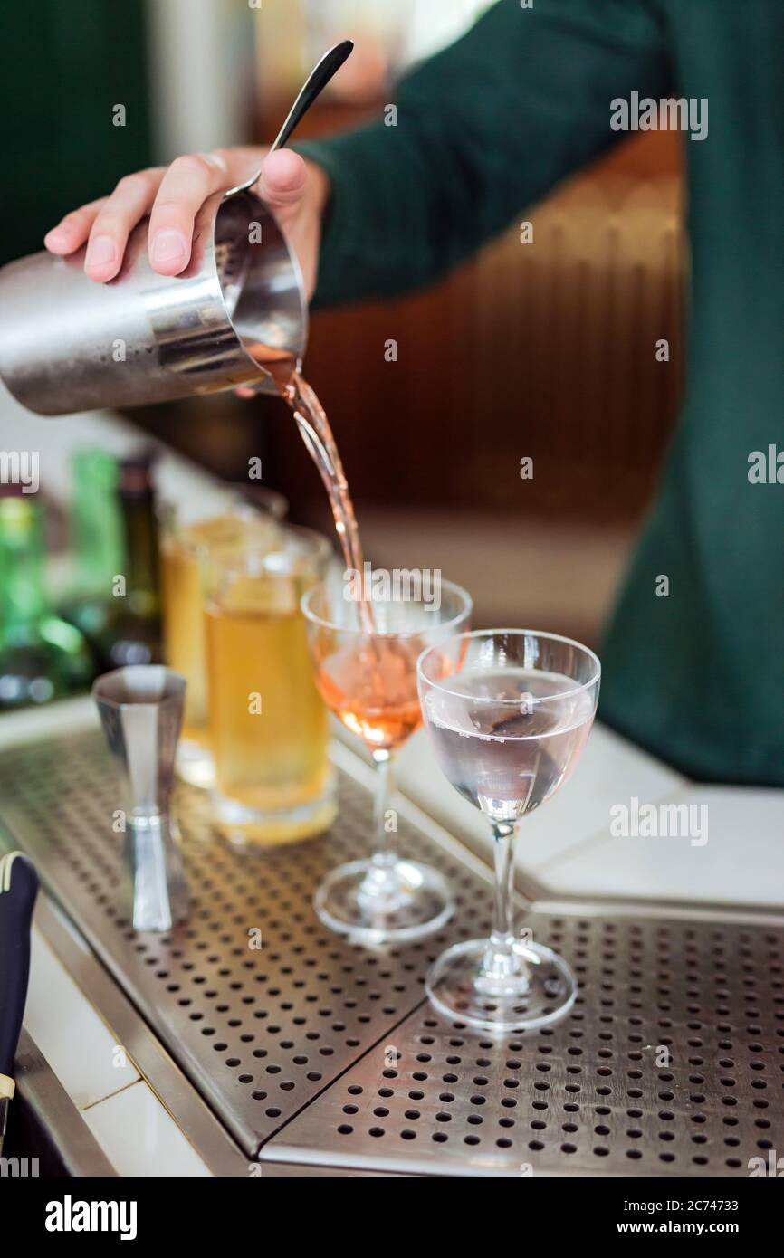 Bartender making a cocktail at the bar: pouring a drink from a shaker ...