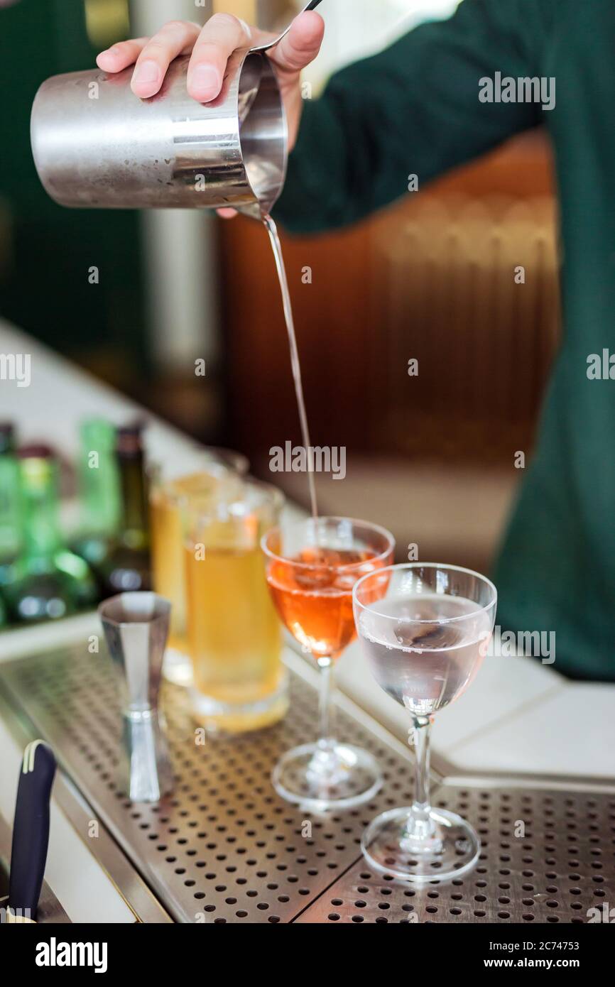Bartender making a cocktail at the bar: pouring a drink from a shaker ...