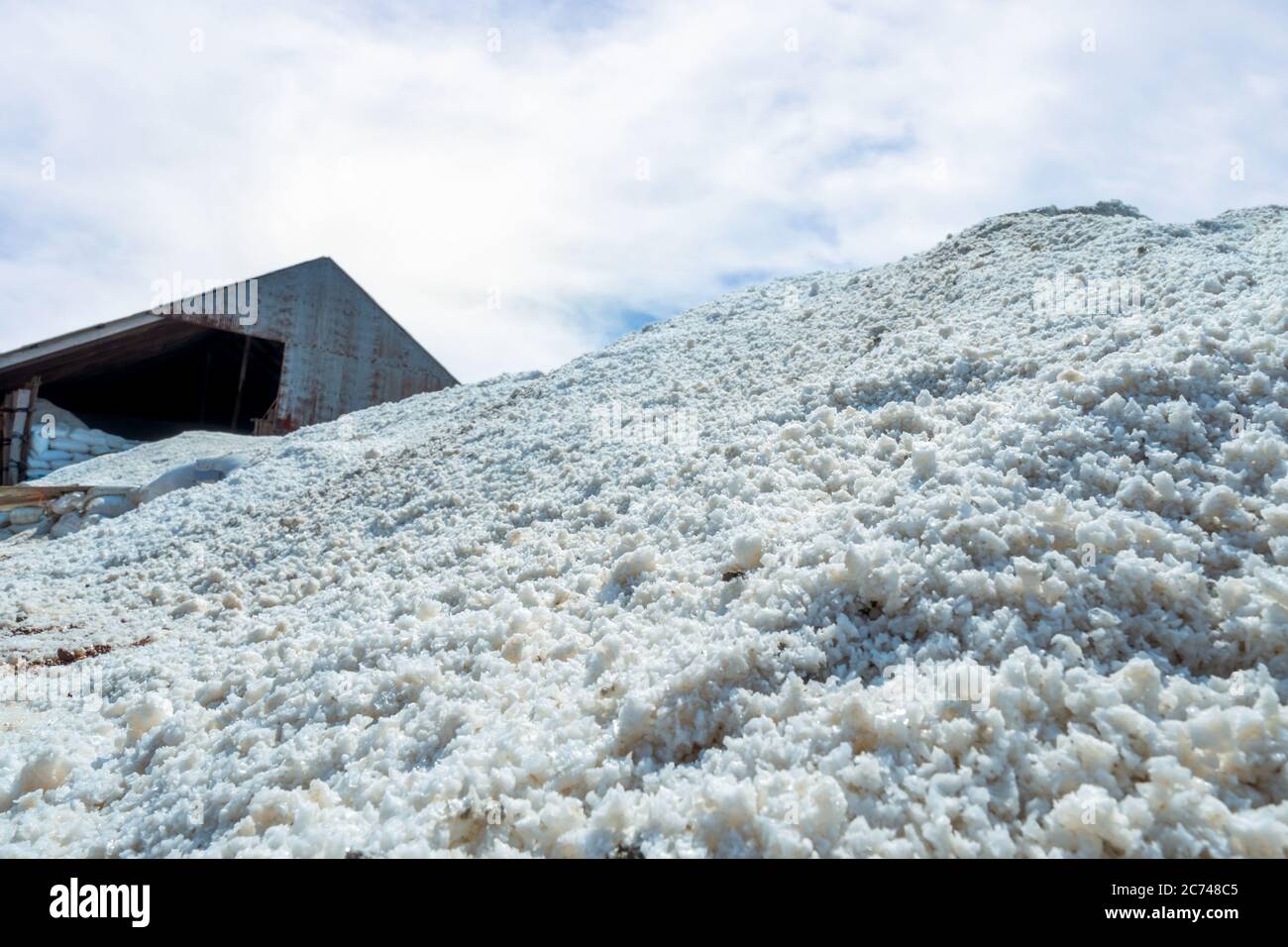 Brine salt farm warehouse with sky and clouds. Pile of organic sea salt ...