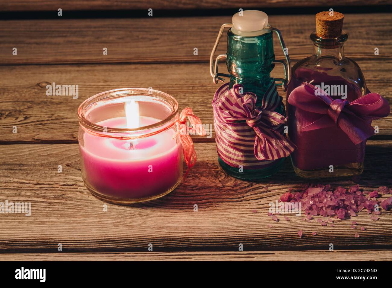 Spa setting with bottles of oil and burning candle Stock Photo - Alamy