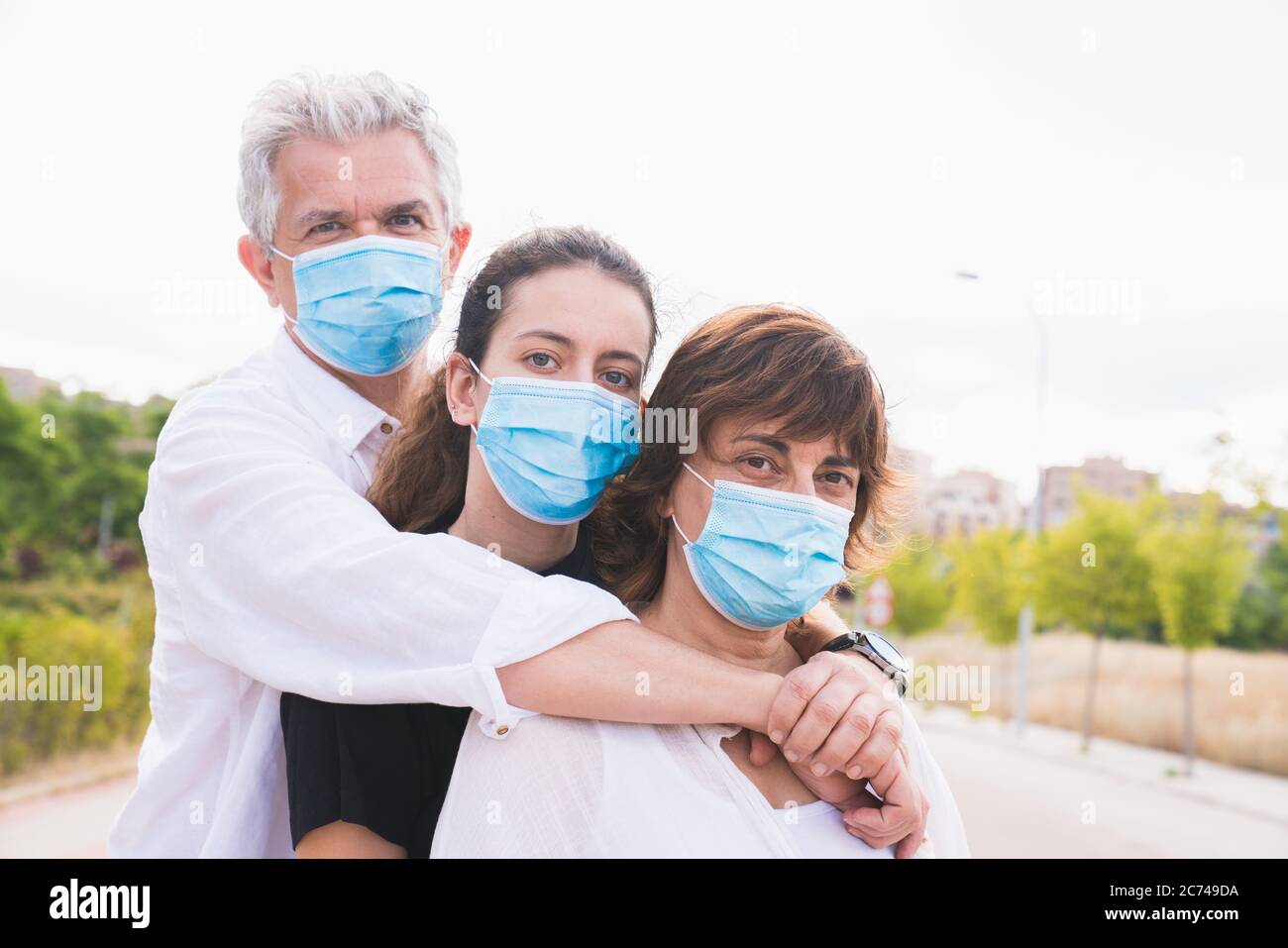 New normal. Masked family hugs. Members of a family hug each other with ...