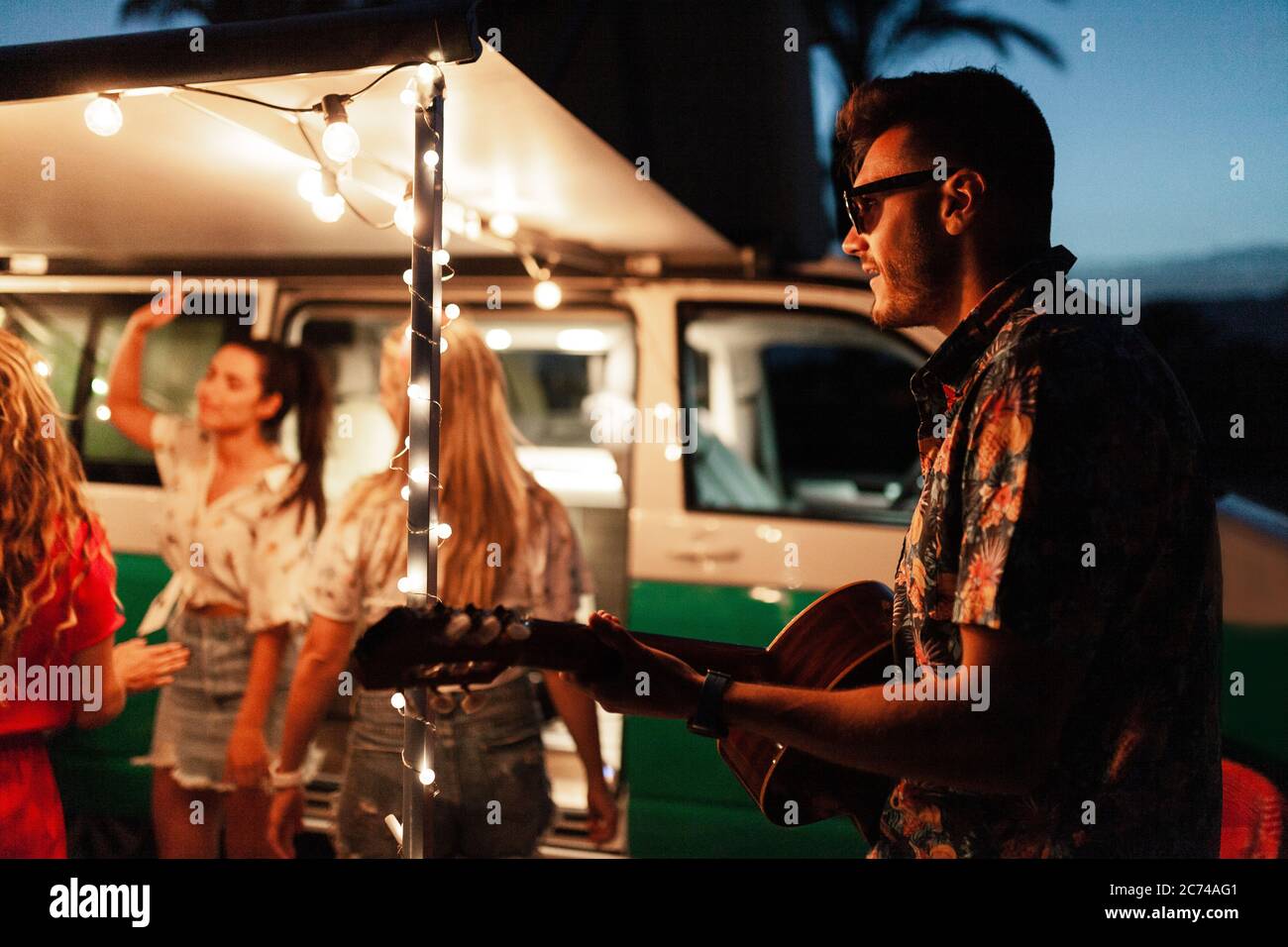 Party men are singing their friends at night near a camper van Stock ...