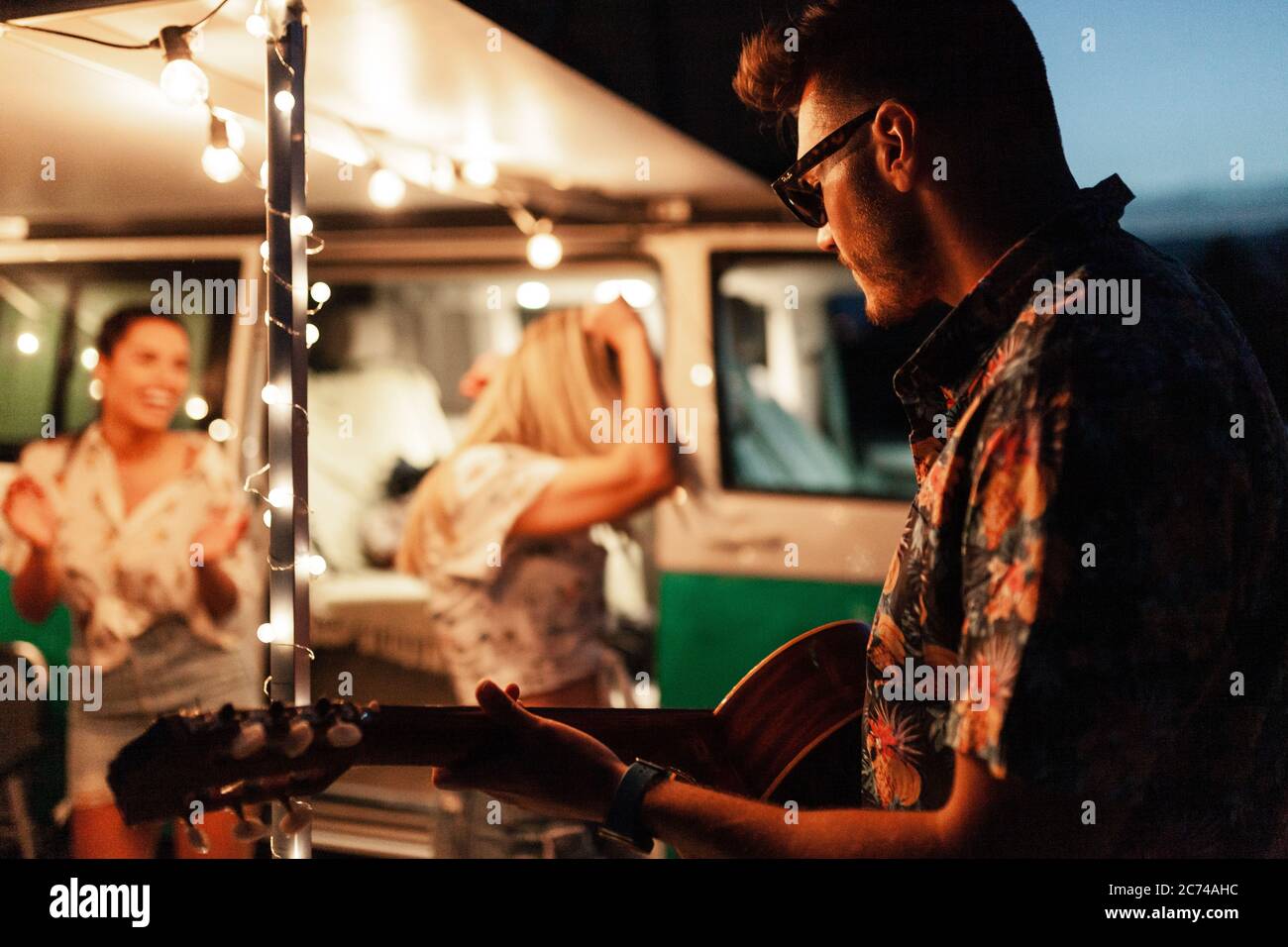 Party men are singing their friends at night near a camper van Stock ...