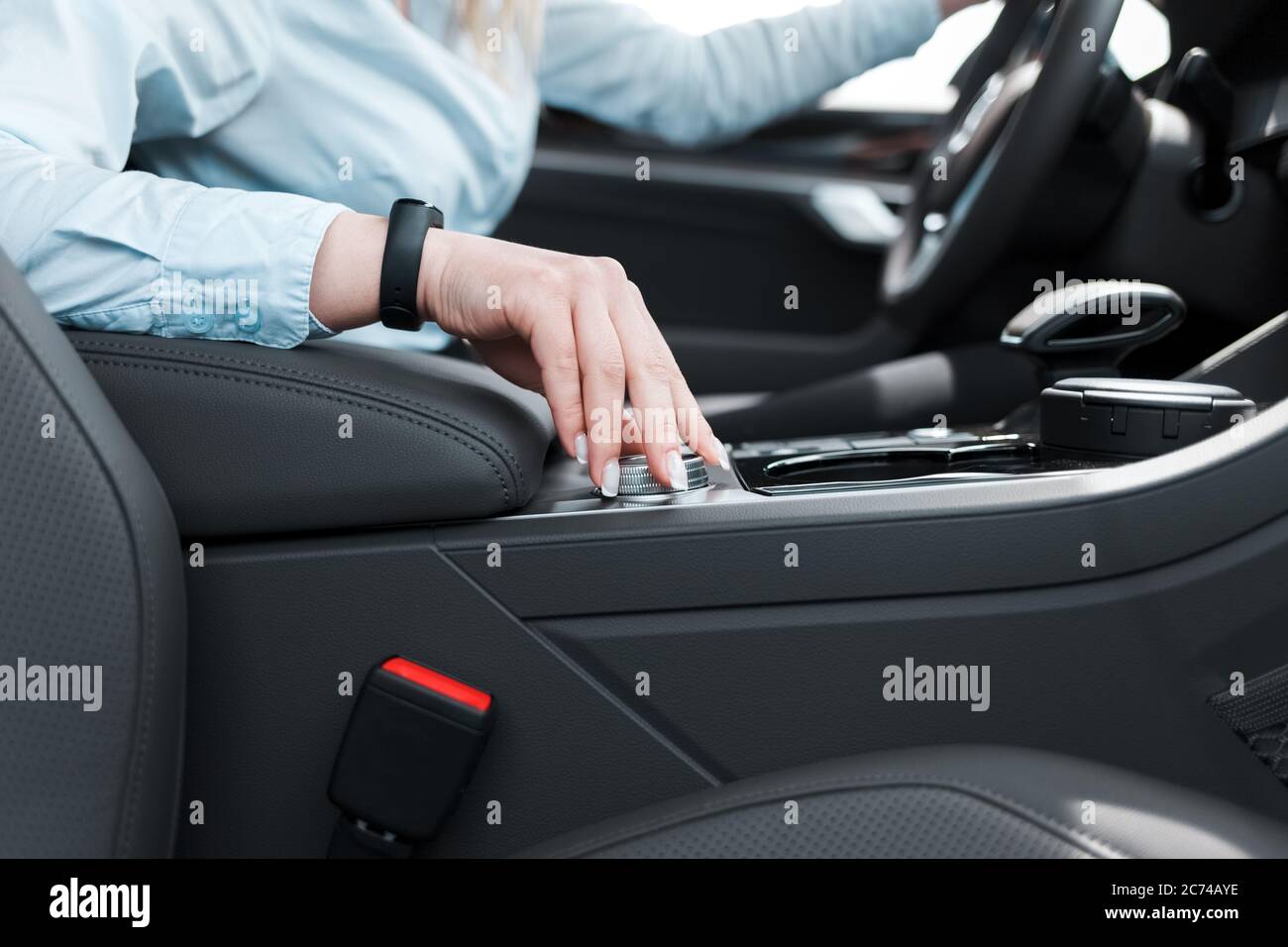 Woman holds her hand on the wheel of the car settings. Ьodern car ...