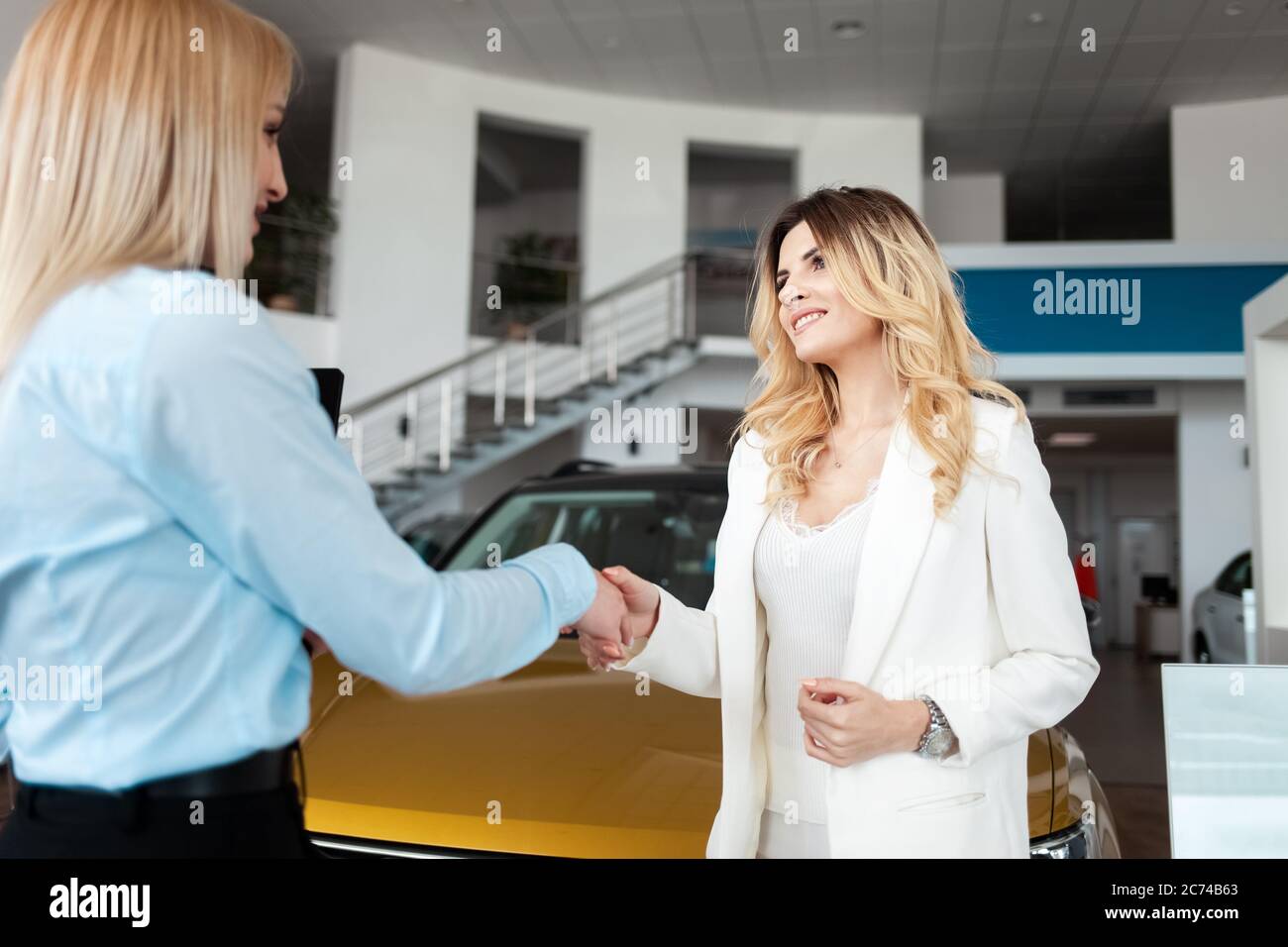 Car dealership seller greeting customer Stock Photo - Alamy