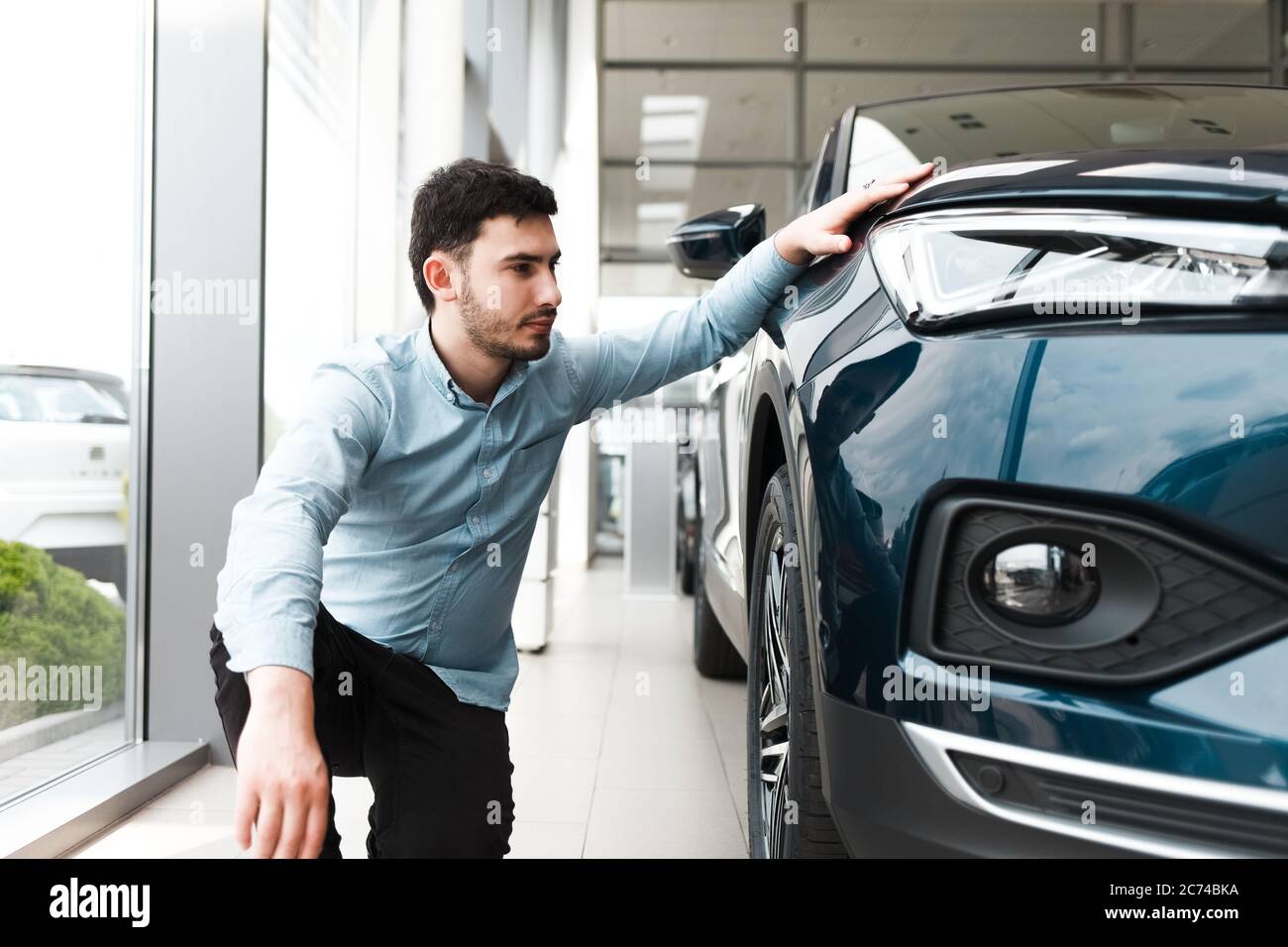 Man holds hand on his new car in a dealership Stock Photo - Alamy
