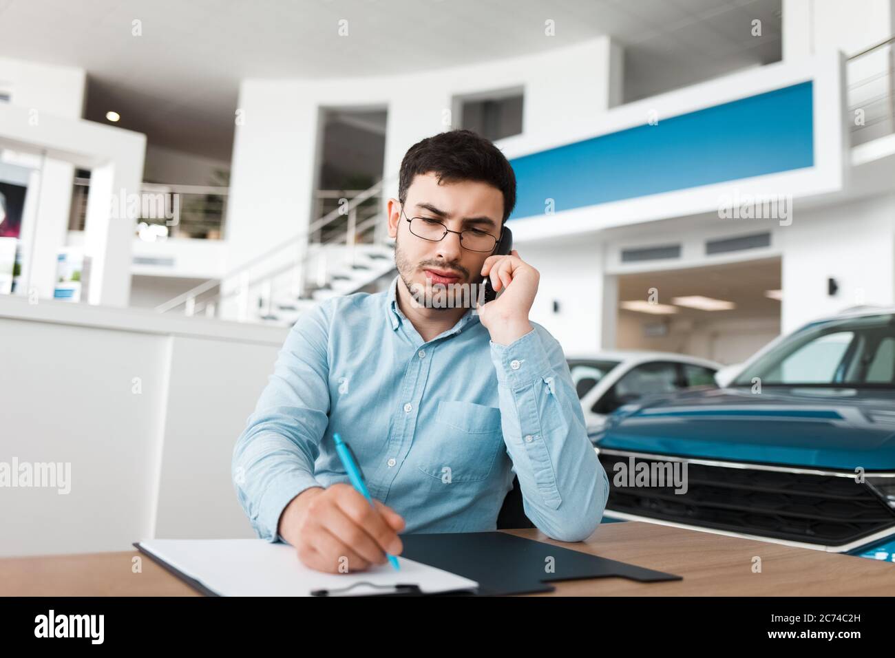 Car dealership employee at the workplace is talking on the phone Stock ...