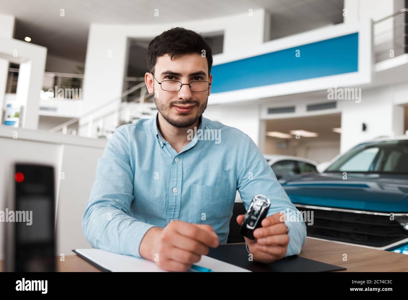 Car dealership employee holding a car key in his hands Stock Photo - Alamy