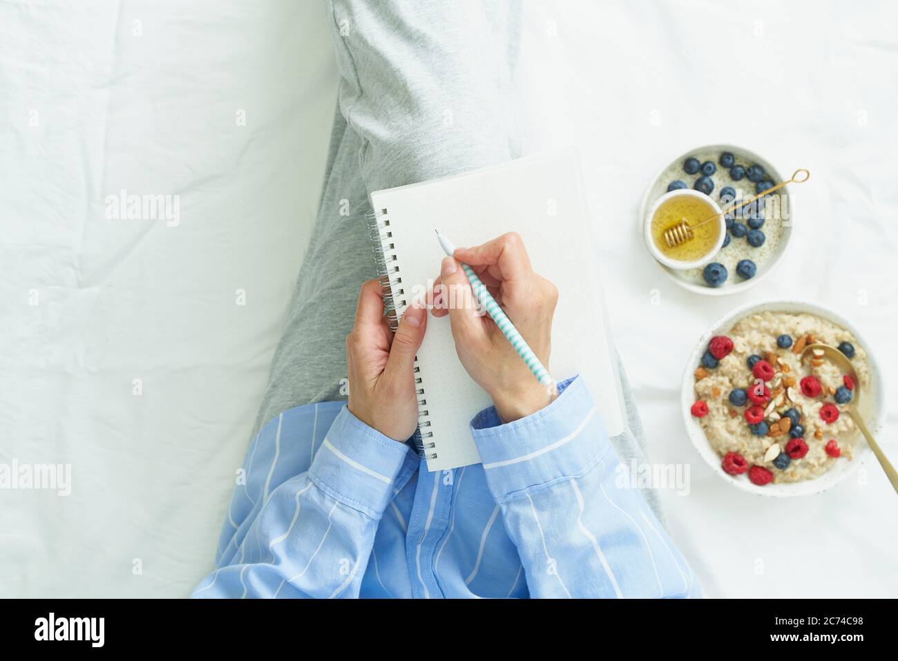 woman writes in large white open notebook, lay on bed Stock Photo - Alamy
