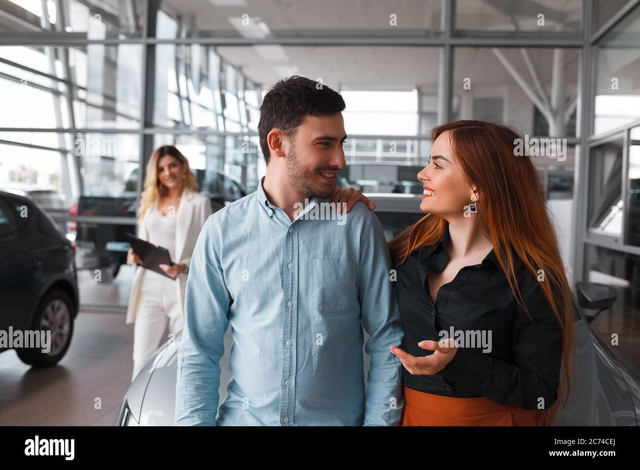 Happy couple at car dealership Stock Photo - Alamy