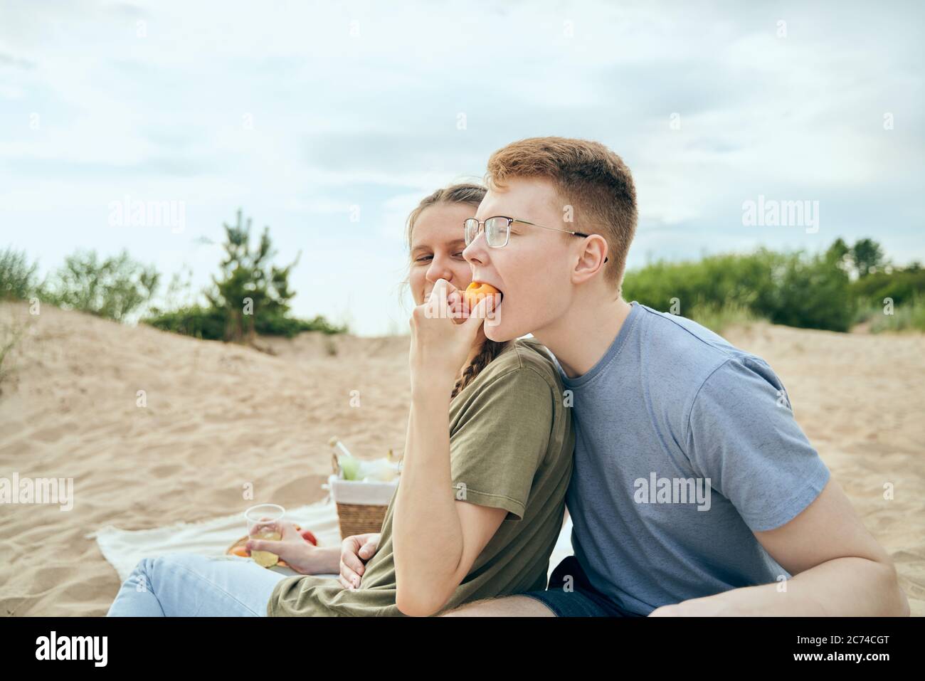 Lovestory of young couple feeding each other on beach Stock Photo - Alamy