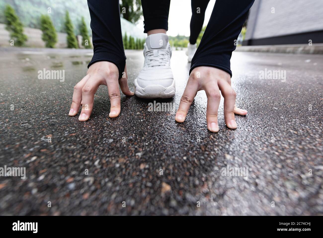 selective focus of runner in white sneakers standing in starting pose ...
