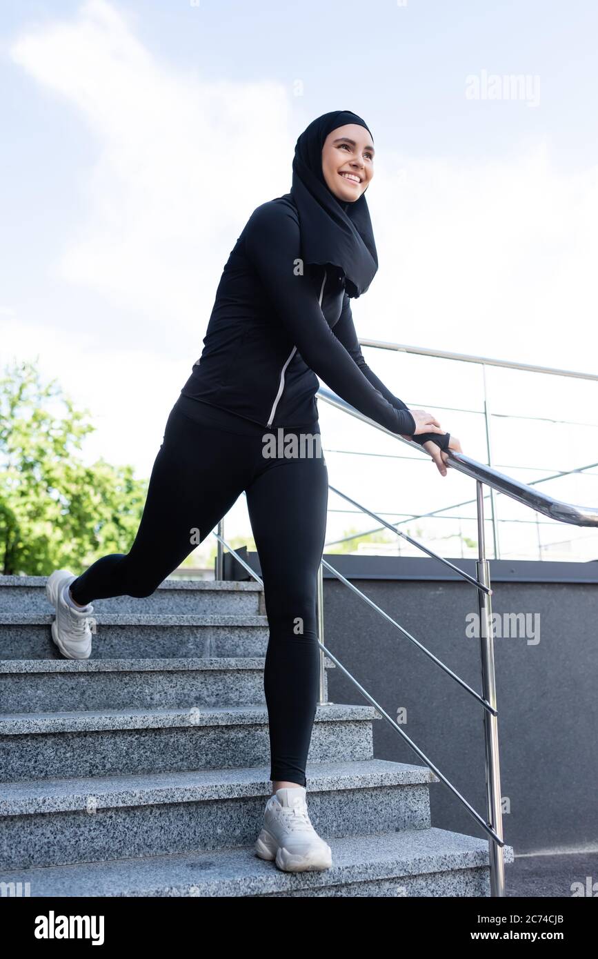 happy muslim sportswoman in hijab walking on stairs outside Stock Photo ...
