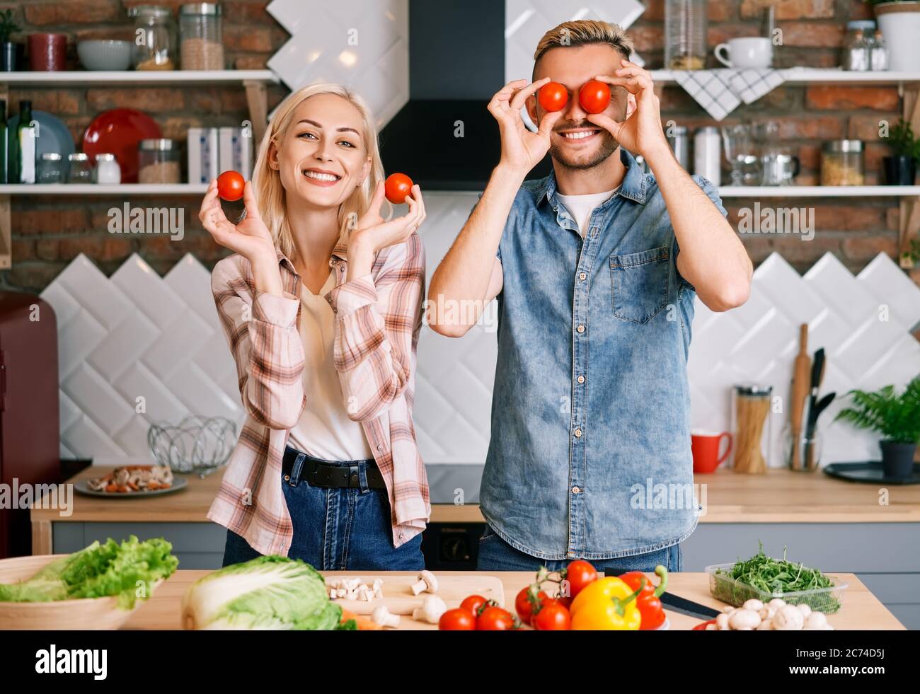 Happy smiling couple having fun cooking together in kitchen at home ...