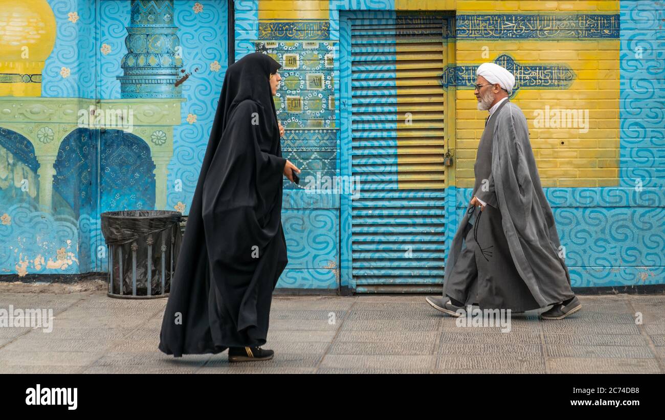 Qom, Iran - May 2019: Iranian man and woman in black dress walking in a ...