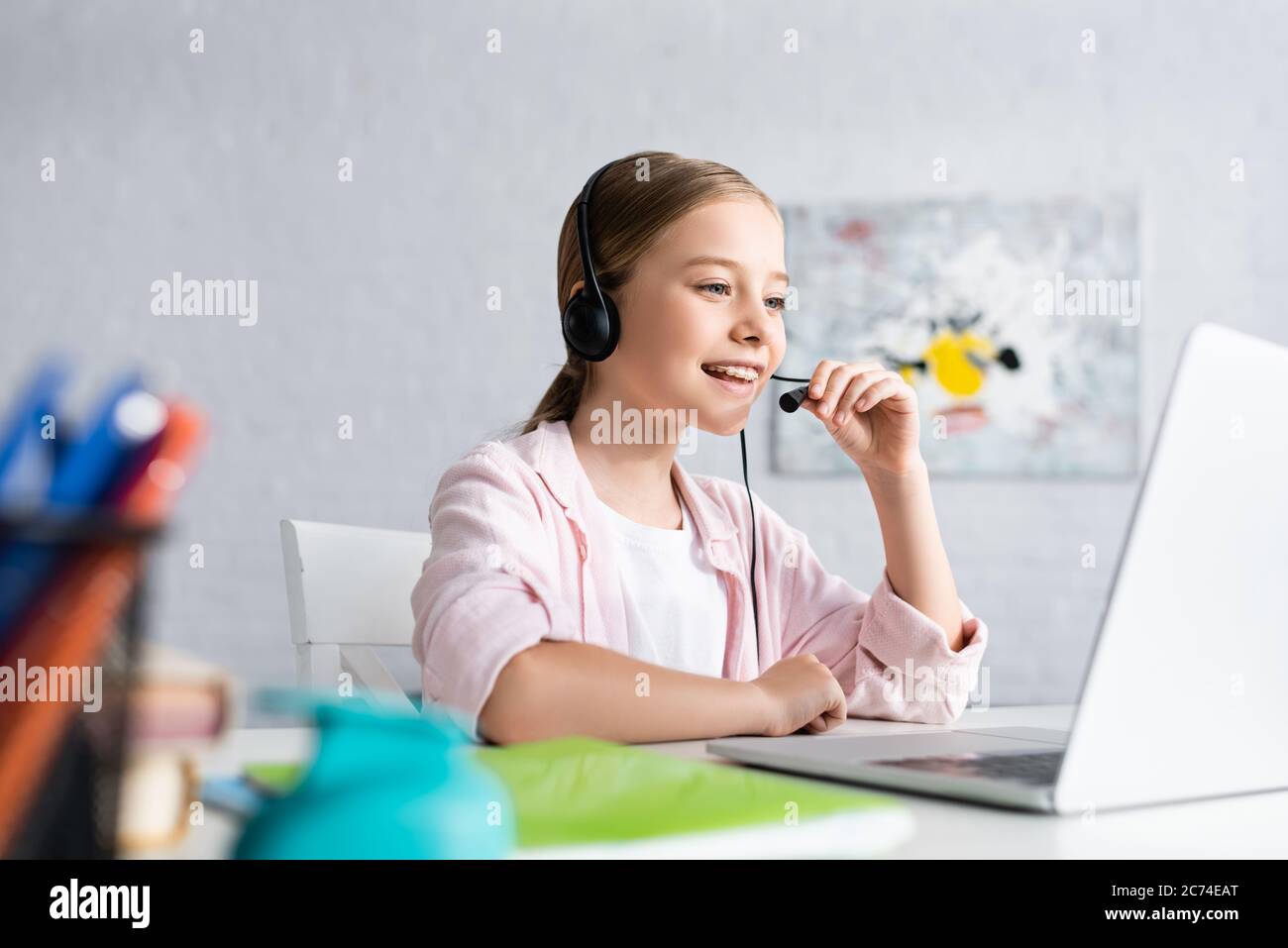 Selective focus of smiling kid using headset during online education ...