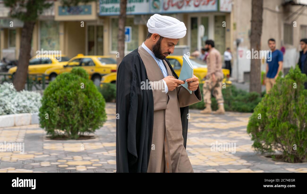 Qom, Iran - May 2019: Iranian man checking his mobile phone in a street ...