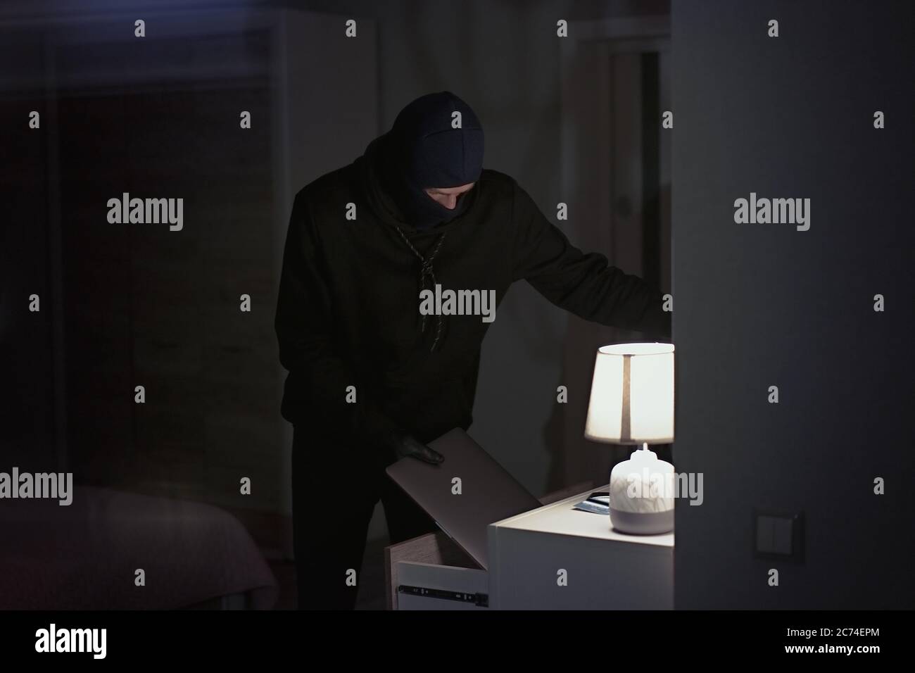 Burglar stealing and putting stolen laptop in bag inside the house at ...