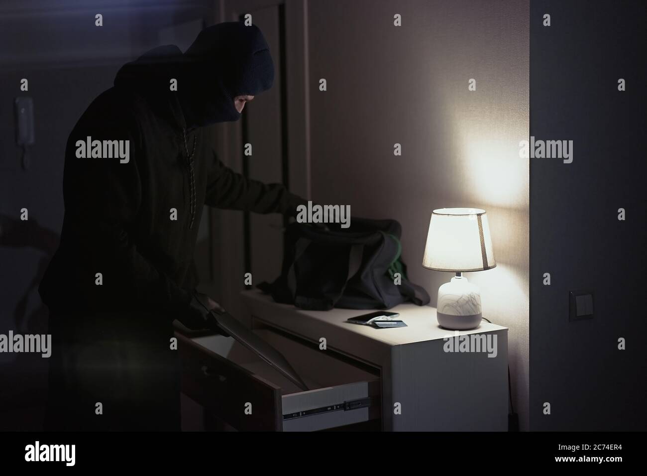 Burglar stealing and putting stolen laptop in bag inside the house at ...