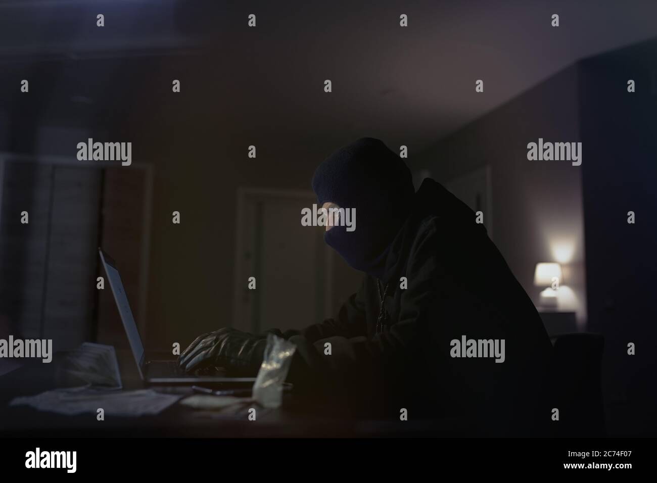 Male hacker in the hood in a dark room using computer virus program for ...