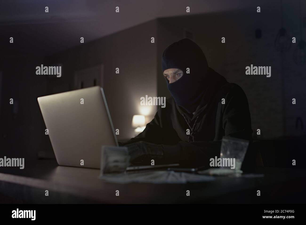 Male hacker in the hood in a dark room using computer virus program for ...