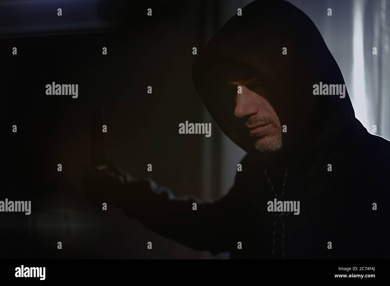 A man with a bloody knife standing in apartment, hands leather gloves ...