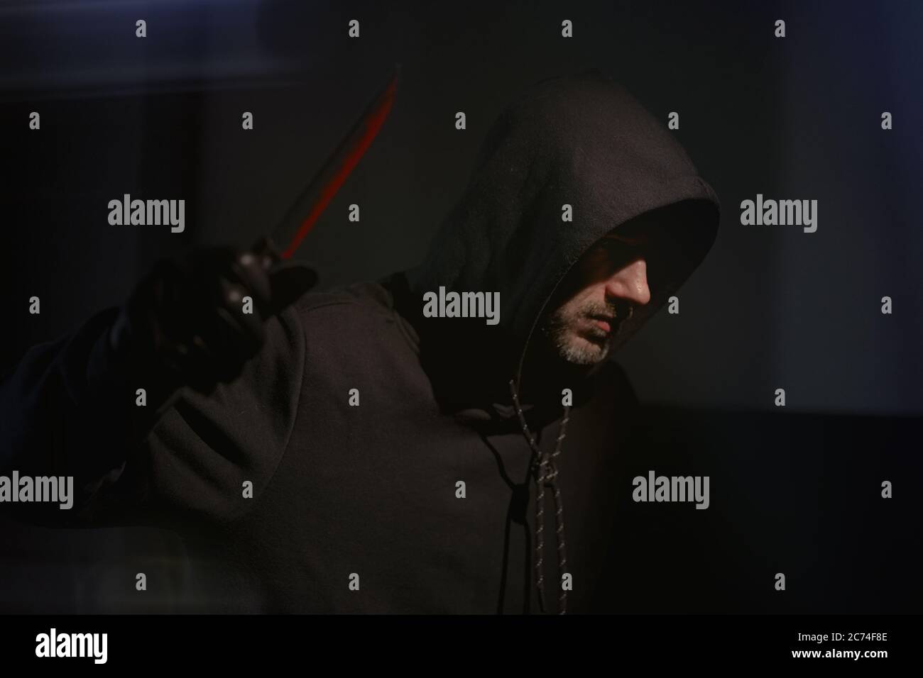 A man with a bloody knife standing in apartment, hands leather gloves ...