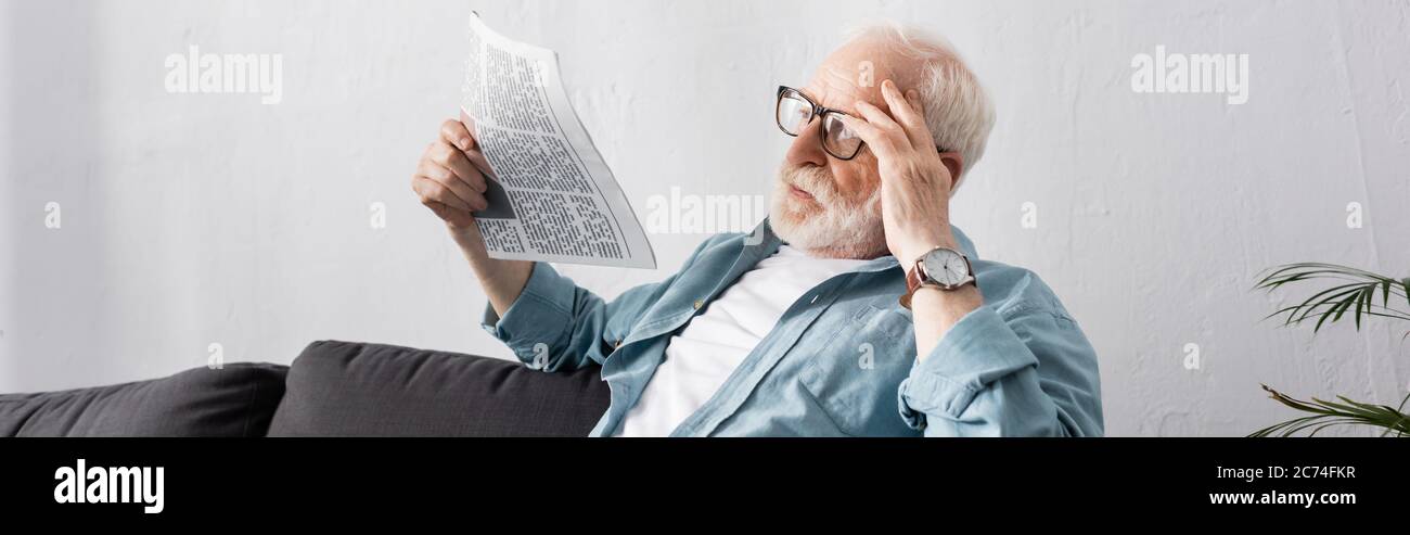 Panoramic orientation of senior man holding newspaper at home Stock ...