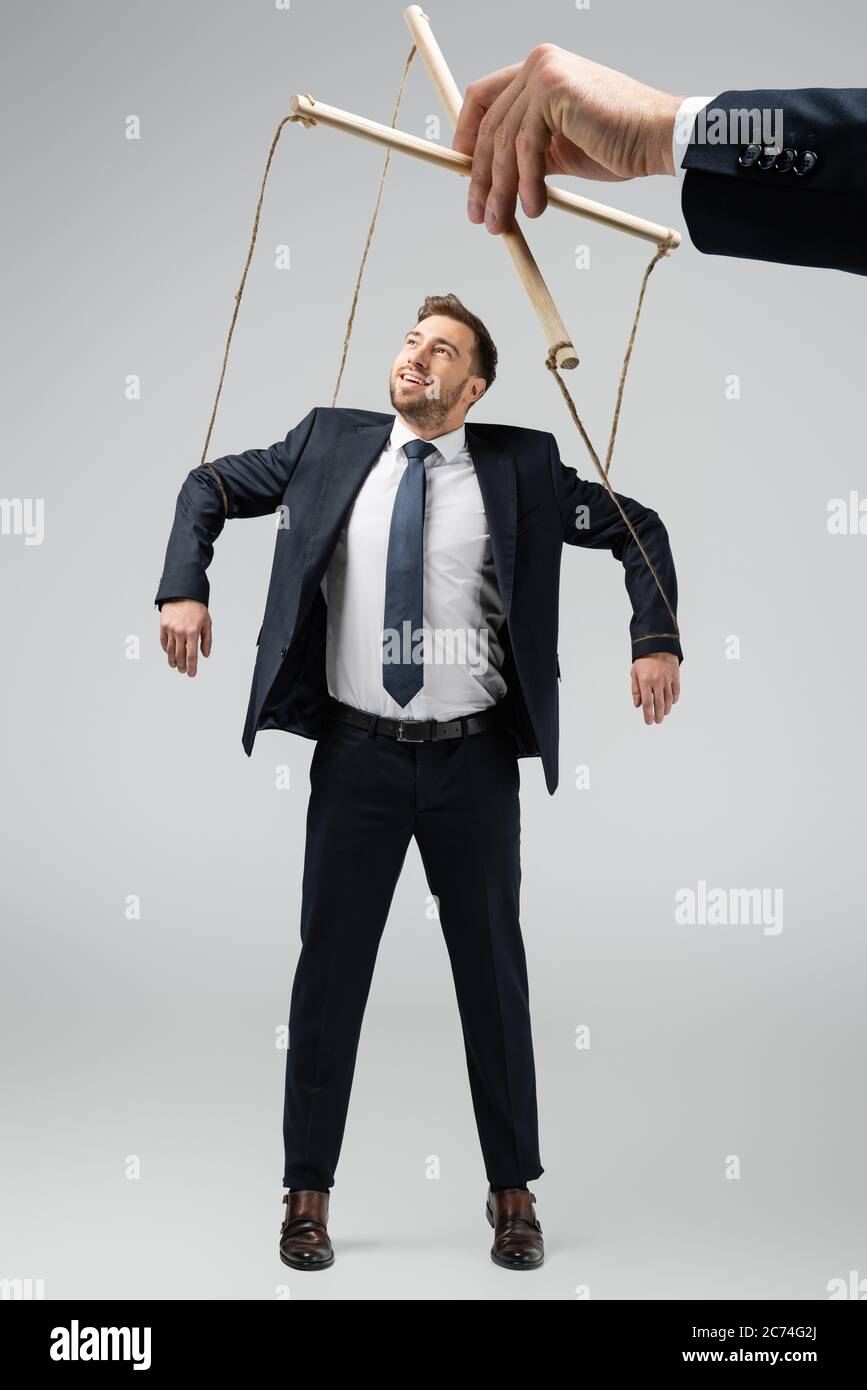 cropped view of puppeteer holding smiling businessman marionette on ...