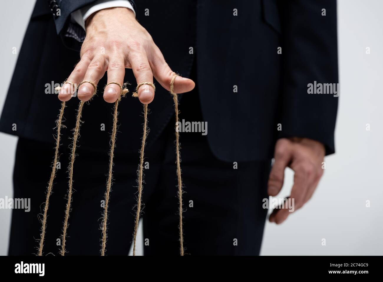 partial view of puppeteer in suit with strings on fingers isolated on ...