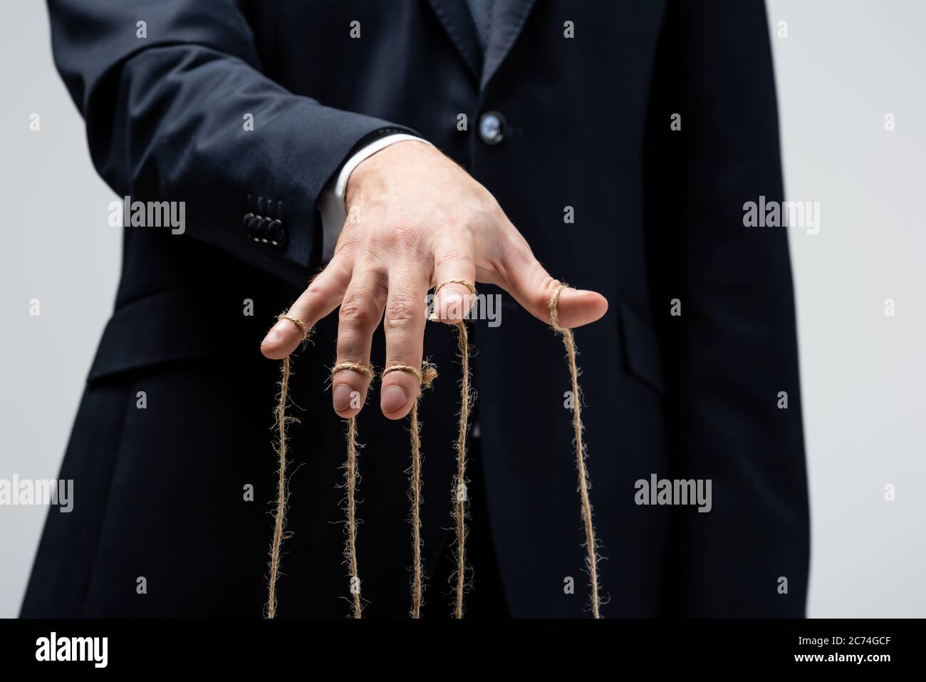 partial view of puppeteer in suit with strings on fingers isolated on ...