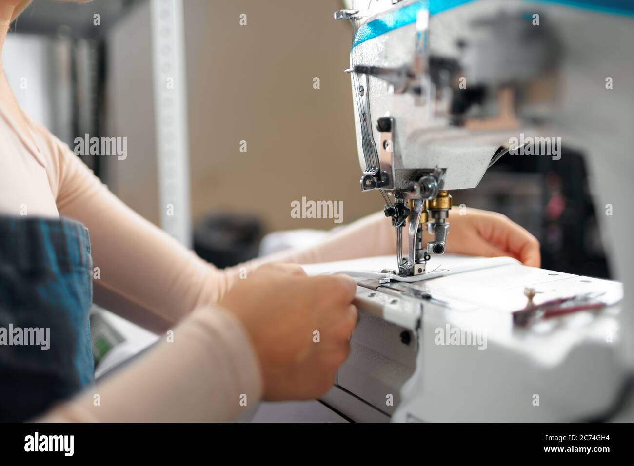 Seamstress woman at her workplace sewing clothes on sewing machine ...
