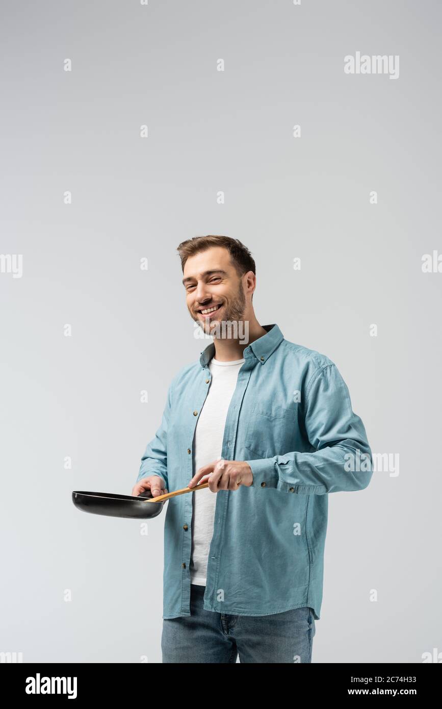 smiling young man with frying pan and spatula isolated on grey Stock ...