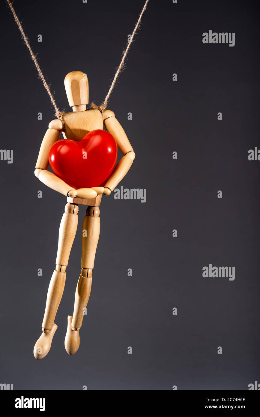 wooden marionette on strings with red heart isolated on black Stock ...